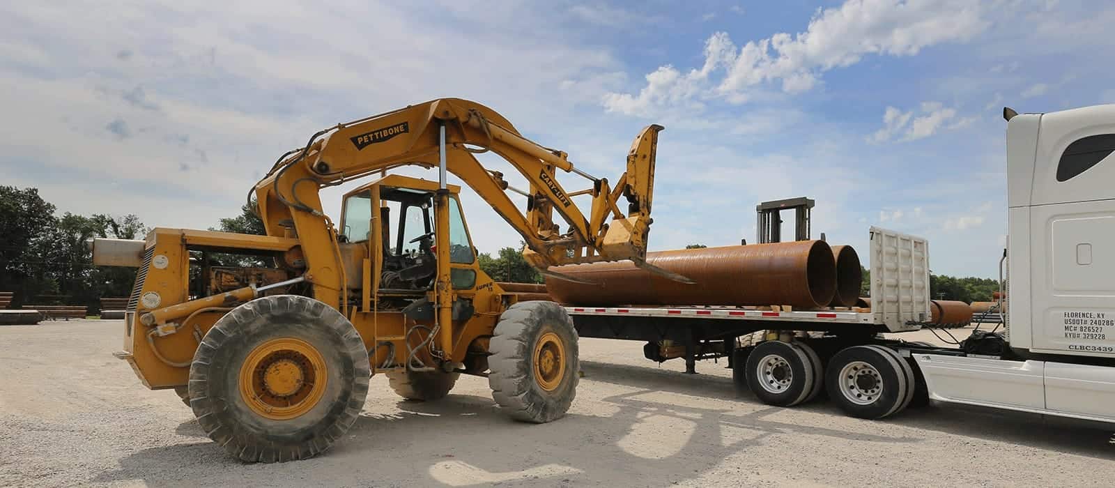 GEOTHERMAL PIPE_Front loader tractor loading large pipes on a truck ...